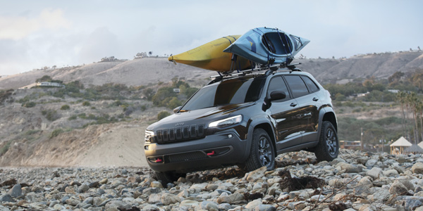 Black 2020 Jeep Cherokee with kayaks on the roof rack driving through a ...